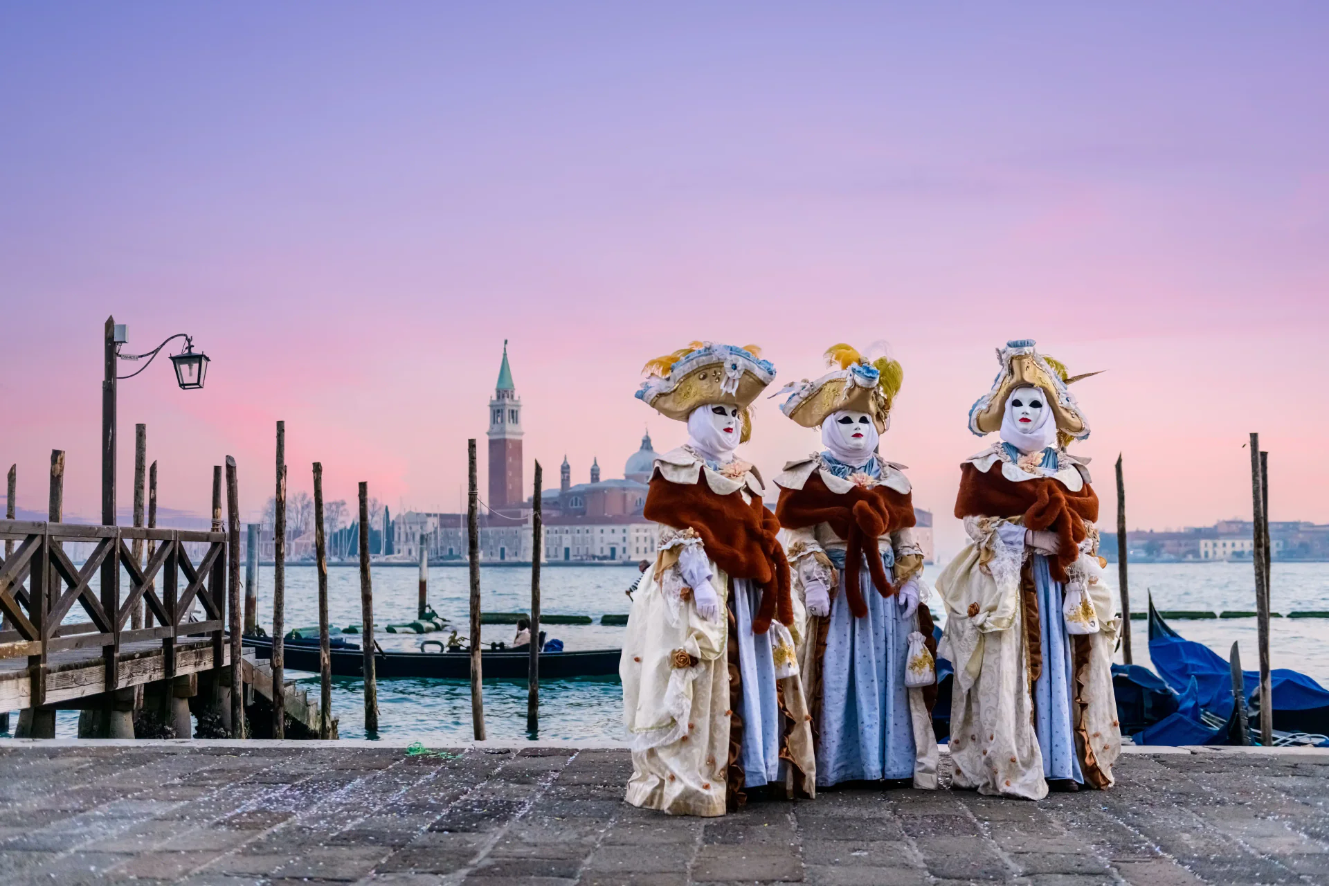 Vue du carnaval de Venise Vue de 3 personnes déguisées pour le Carnaval de Venise devant la place Saint-Marc située en arrière plan